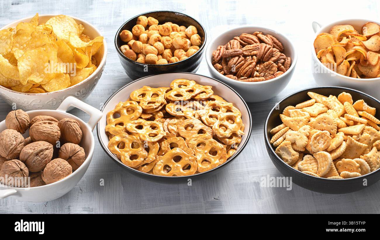 Different kinds of snacks, chips, nuts, popcorn and cookies on a grey ...