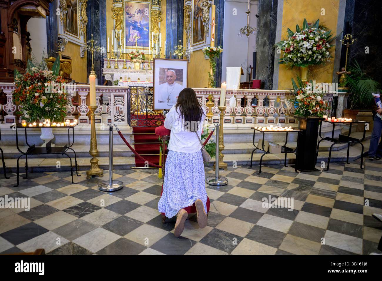 A south american tourist pray in front of a portrait of Pope Francis ...