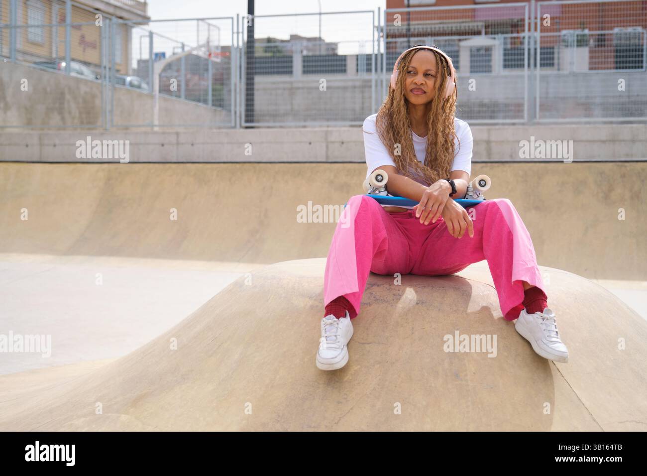 Stylish skater listening to music in skate park sitting on ramp Stock ...