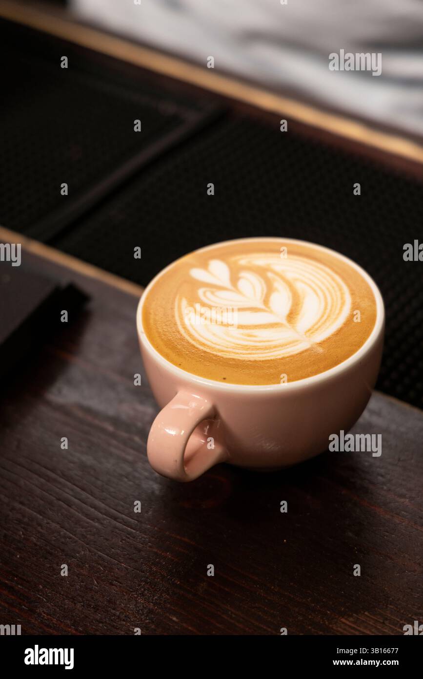 A Cafe Latte with art sits on counter vertical Stock Photo - Alamy