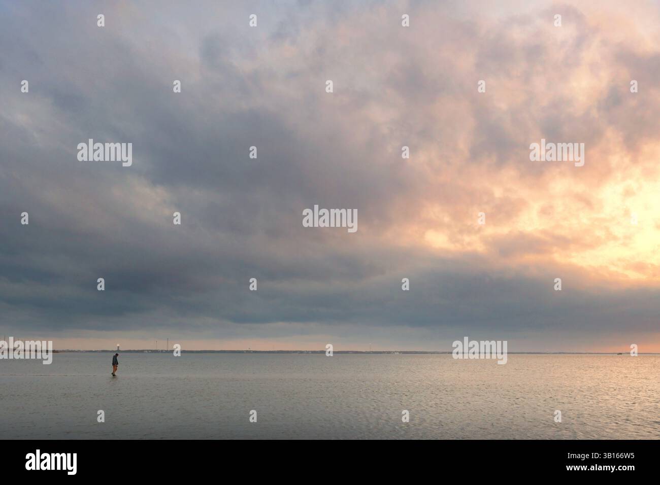 Profile of person walking on sandbar at sunset Cape Hatteras Nat Stock ...
