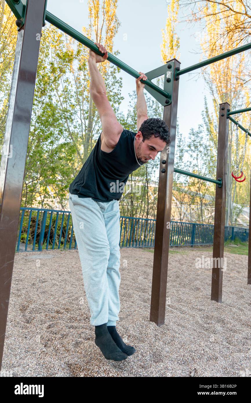 Man hanging from calisthenics bar in position of Skin the Cat exercise ...