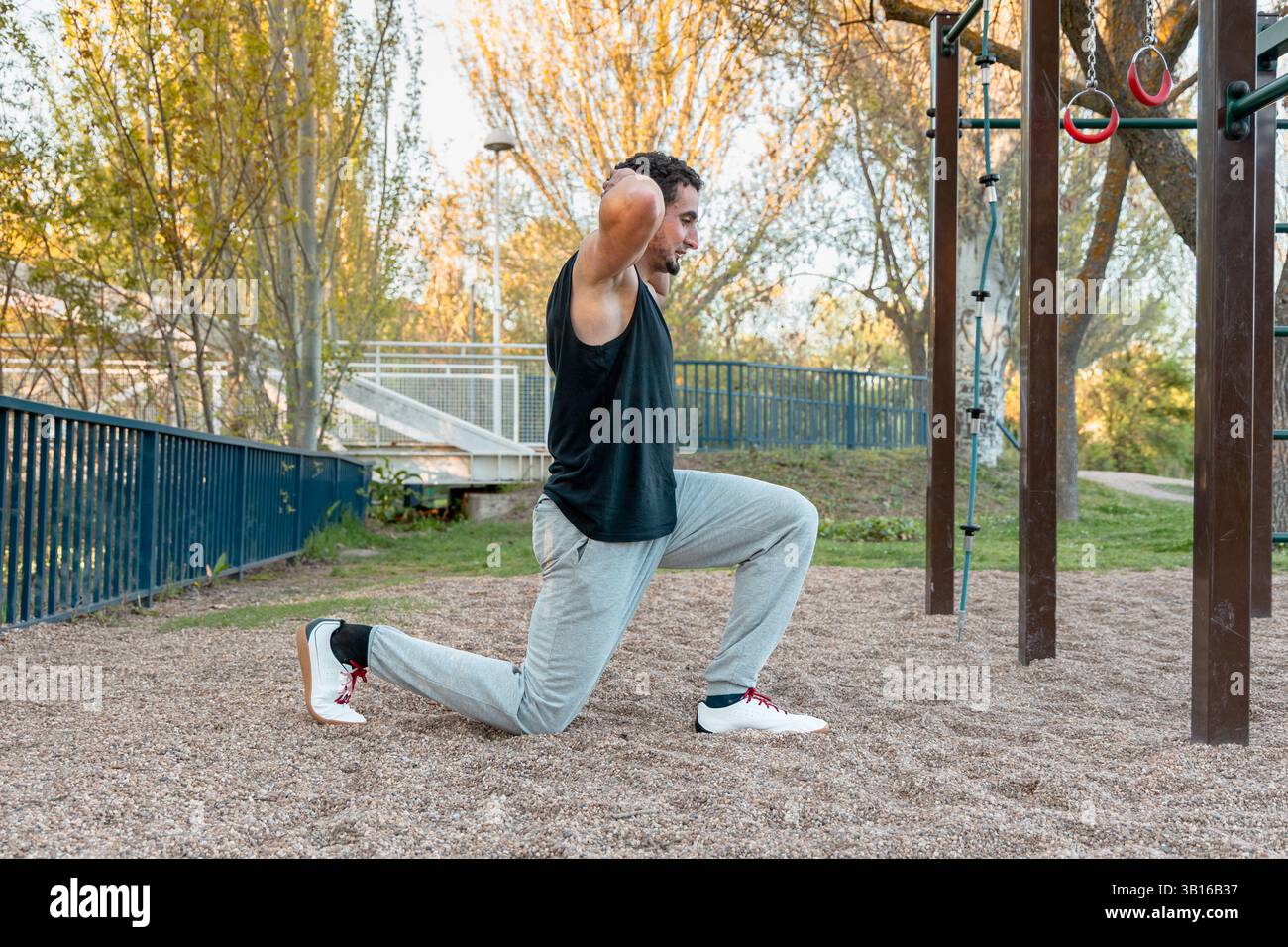 Man performing bodyweight lunge with hands behind head outdoors ...