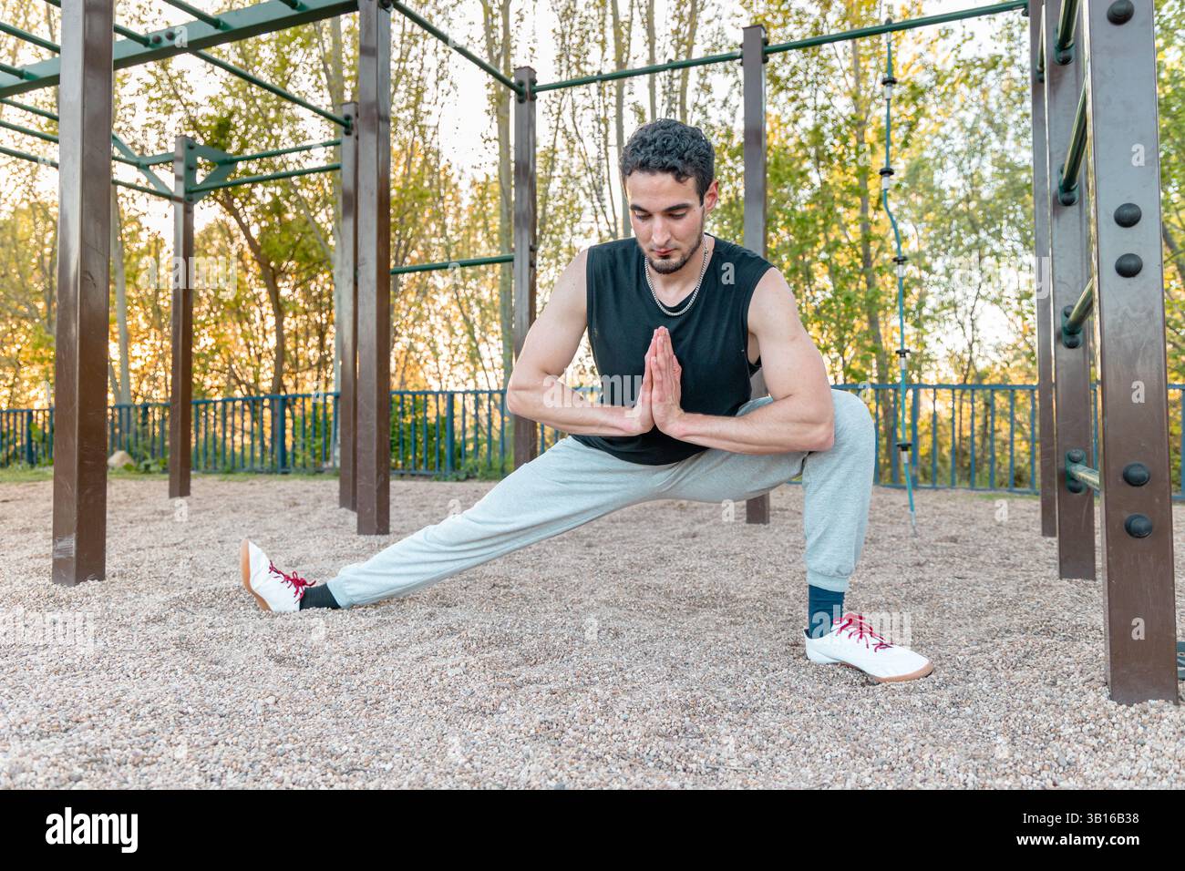Athletic man in Cossack squat stretch outdoors, improving lower body ...