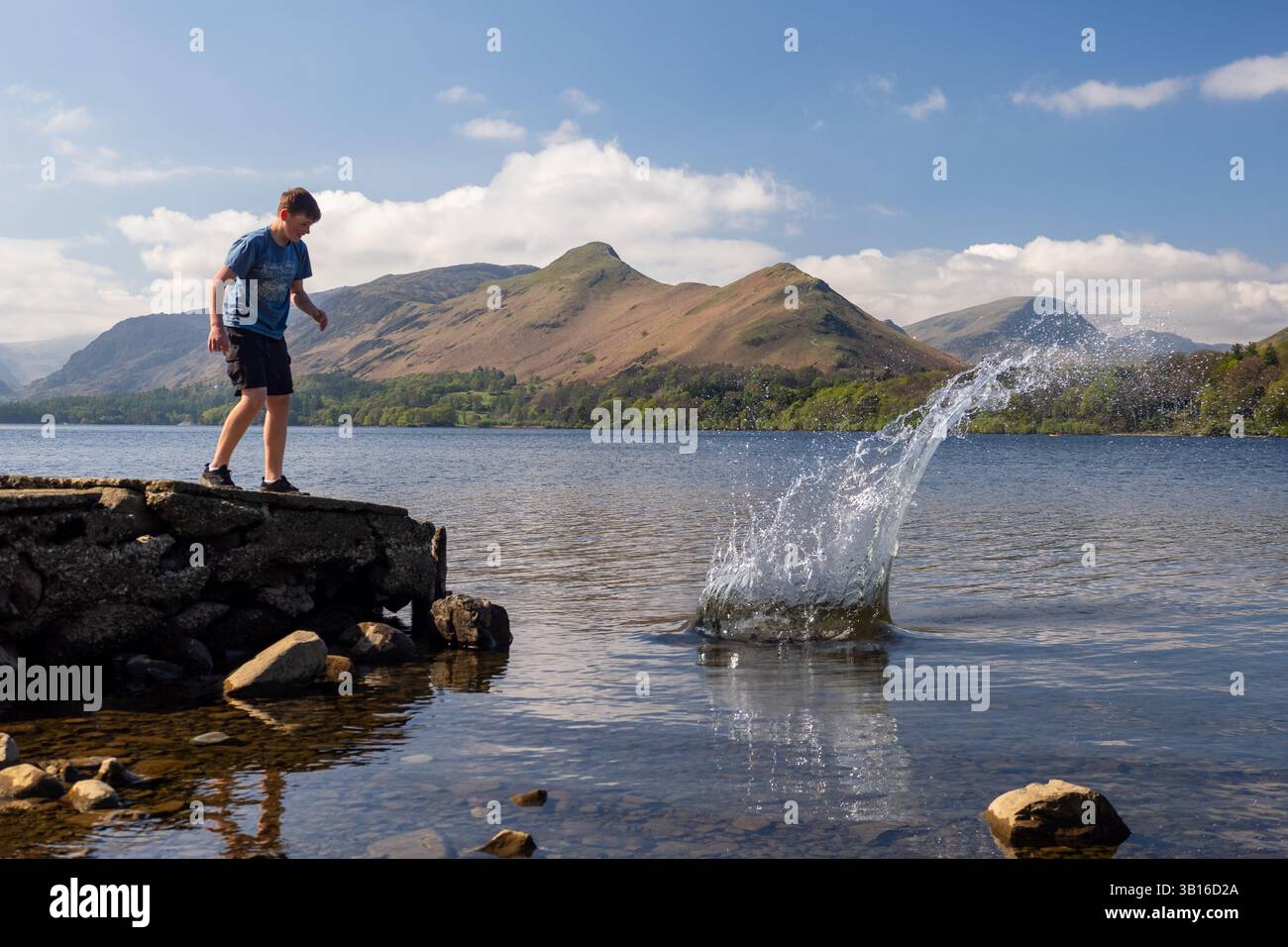 A teenage boy throwing a stone into Derwent Water, the Lake District ...