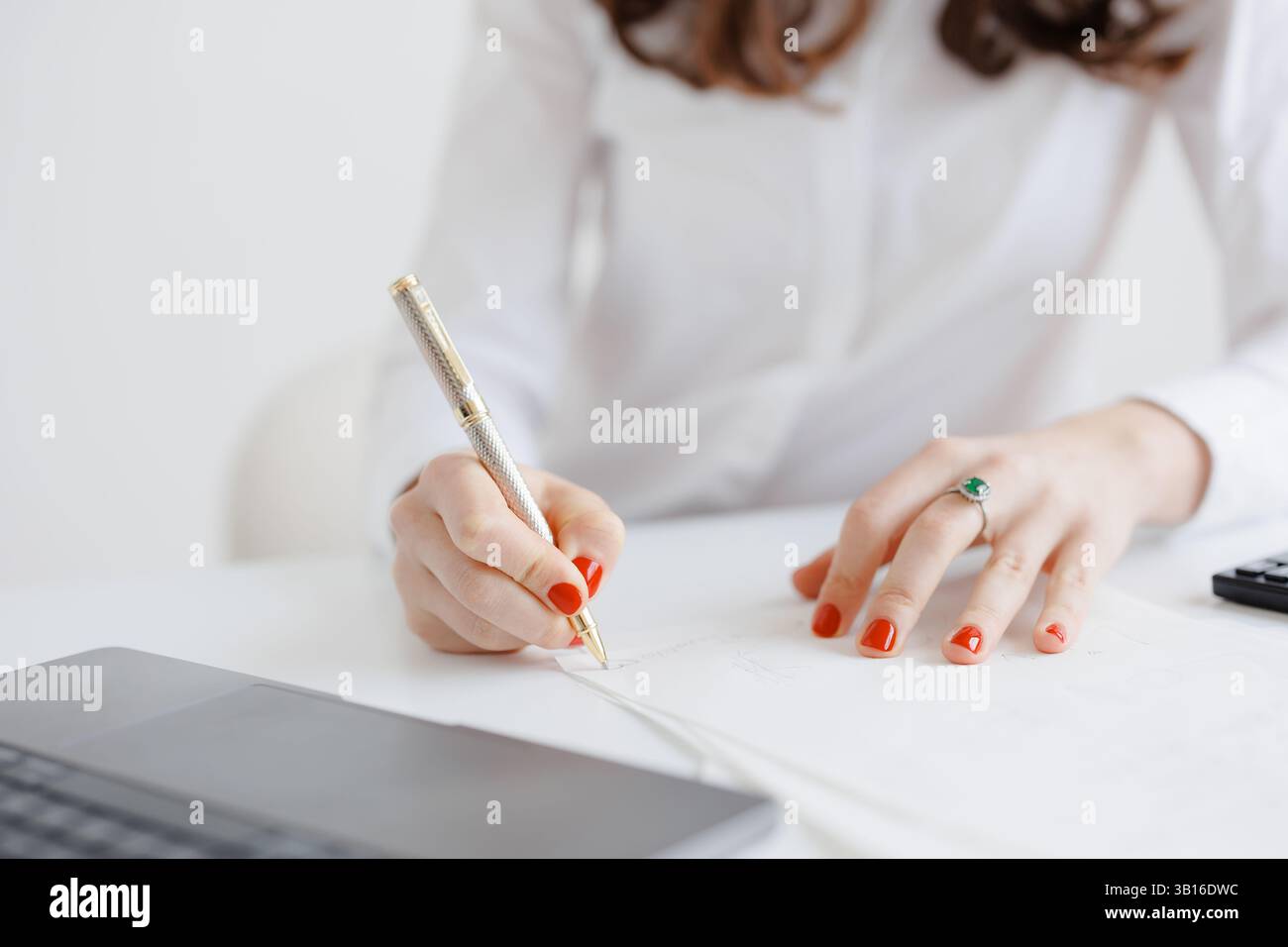 Professional woman writing notes with elegant pen while sitting at desk ...