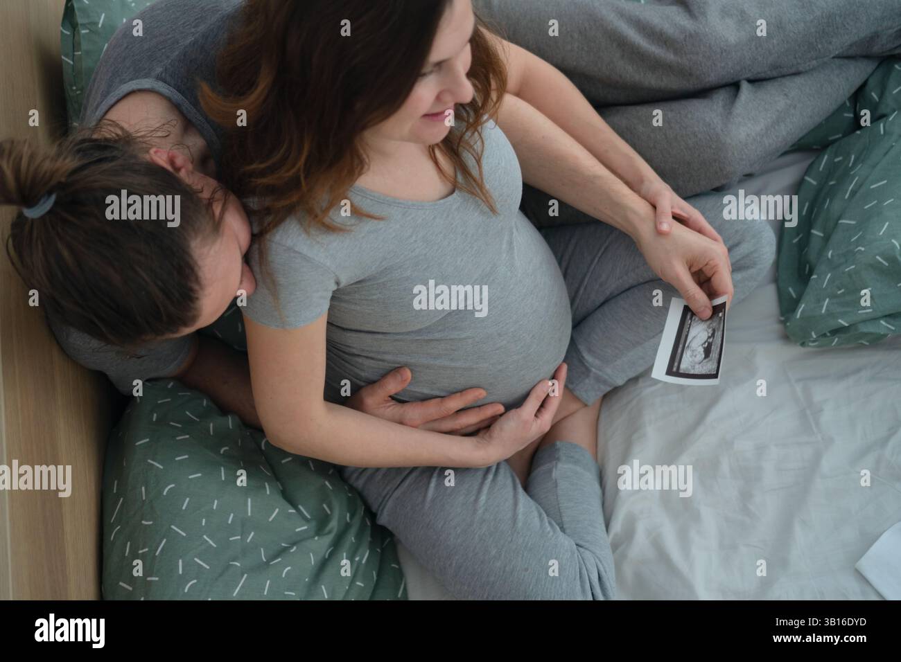 Aerial view shows expecting mother in lotus pose holding ultrasound ...