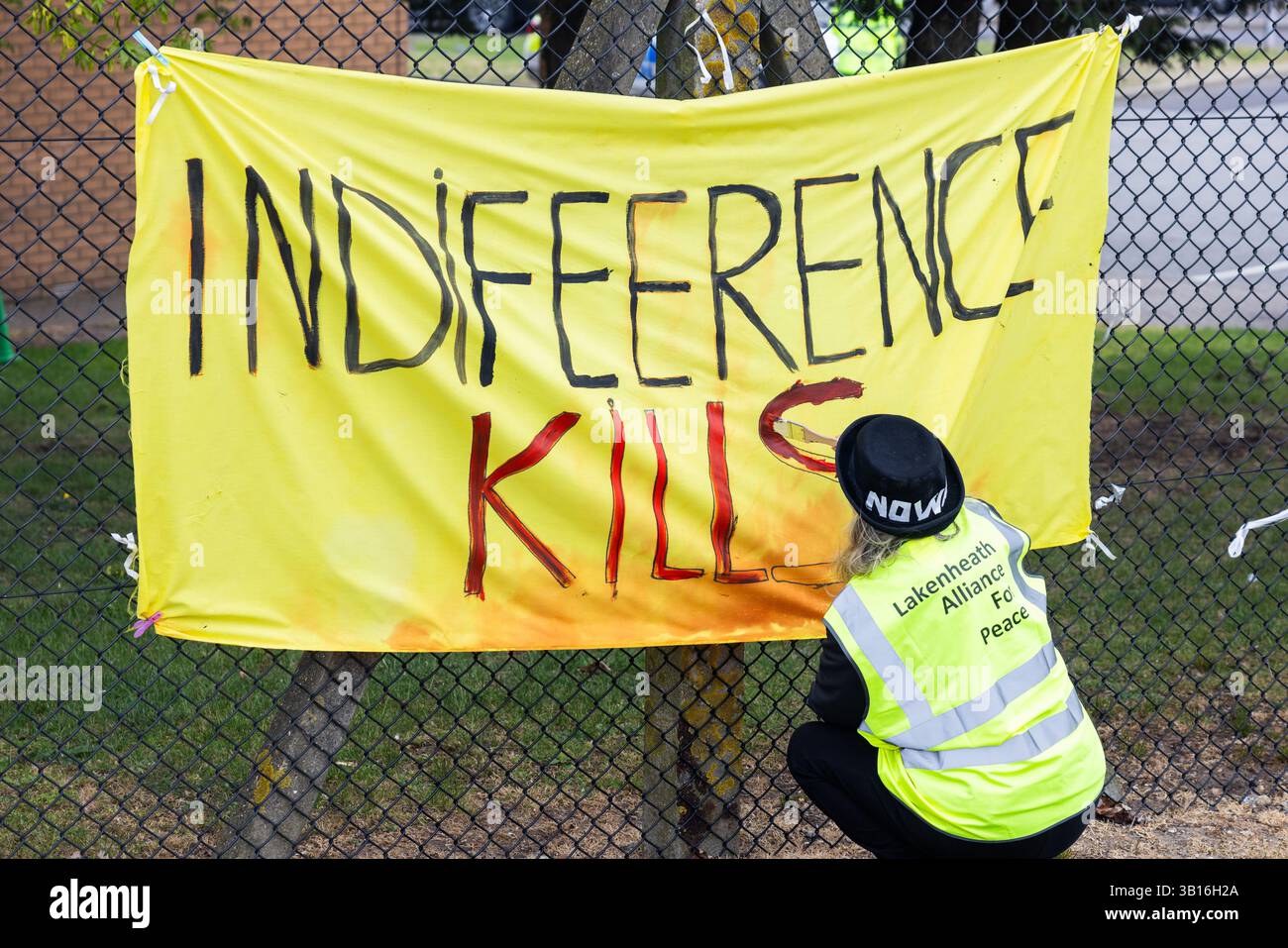 Lakenheath, UK. 25 APR, 2025. Person paints "Indifference Kills" banner ...