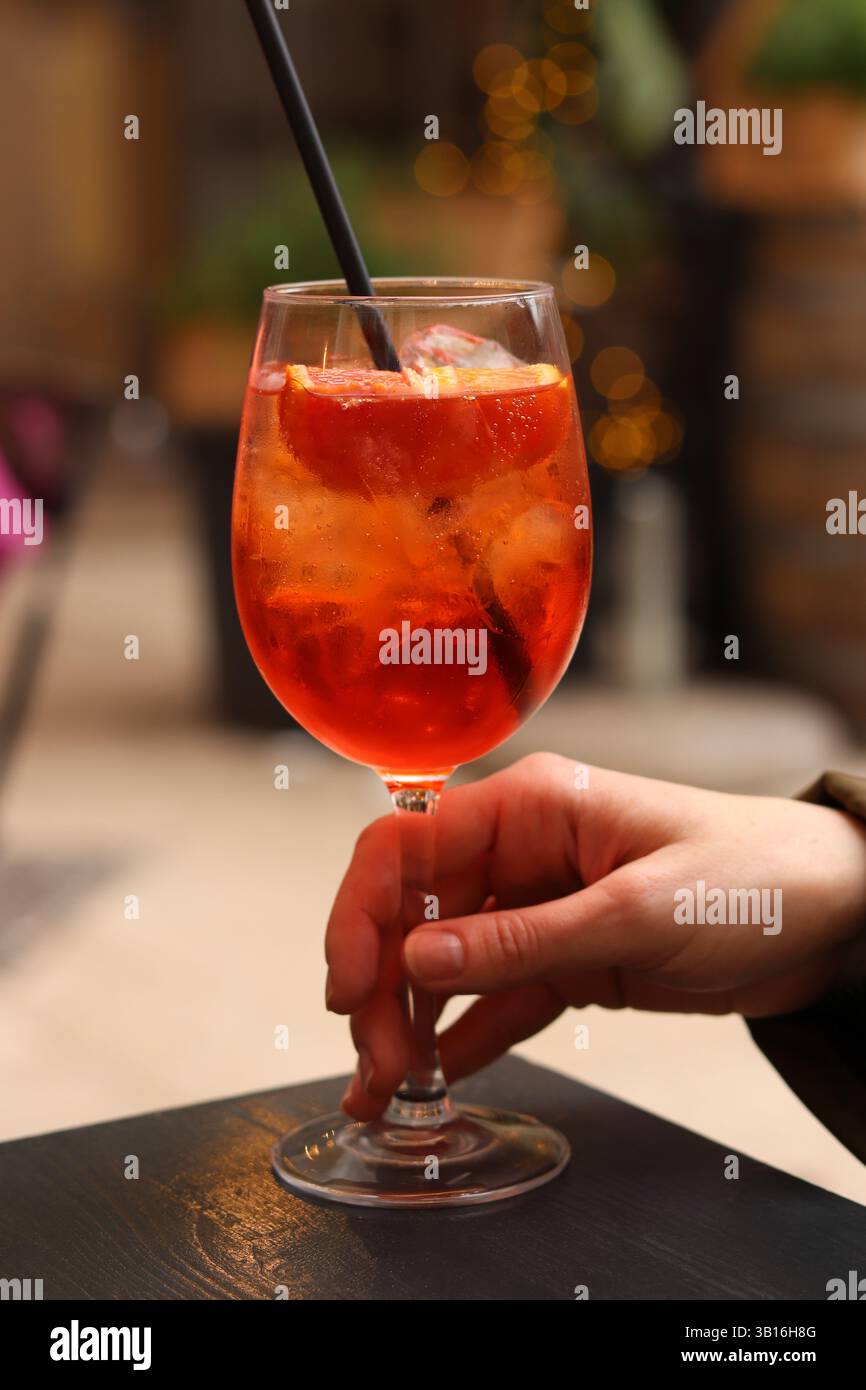 Glass with Aperol Spritz in a woman's hand. Cold refreshing alcoholic ...