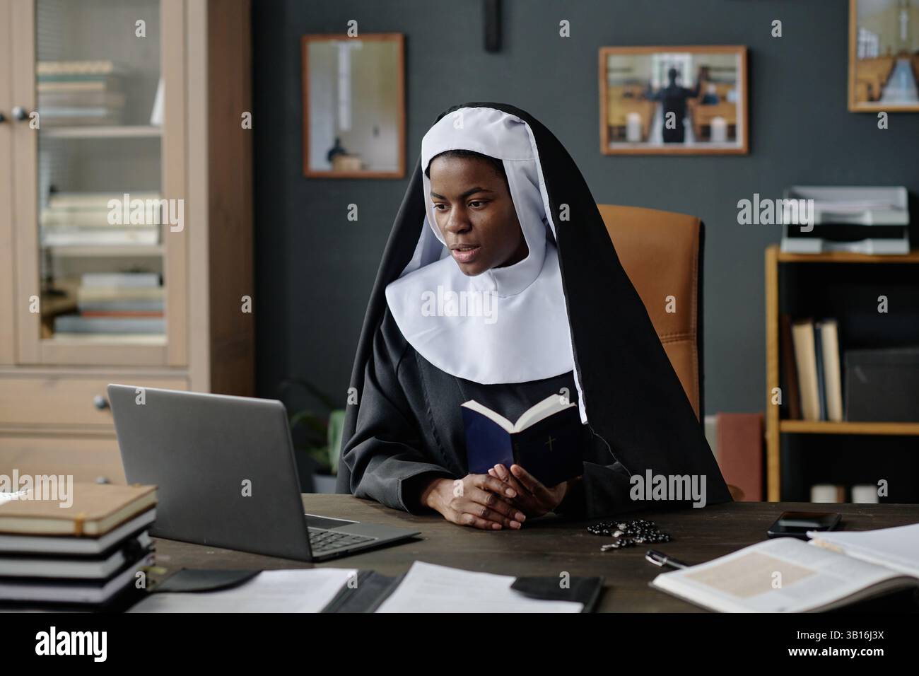 Medium shot of young adult African American nun holding bible in two ...