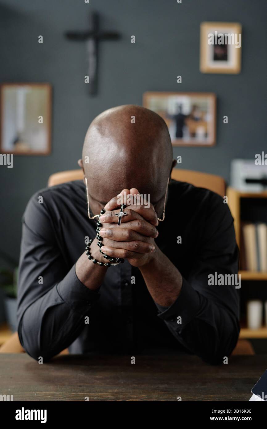 Vertical shot of African American pastor praying silently alone in ...