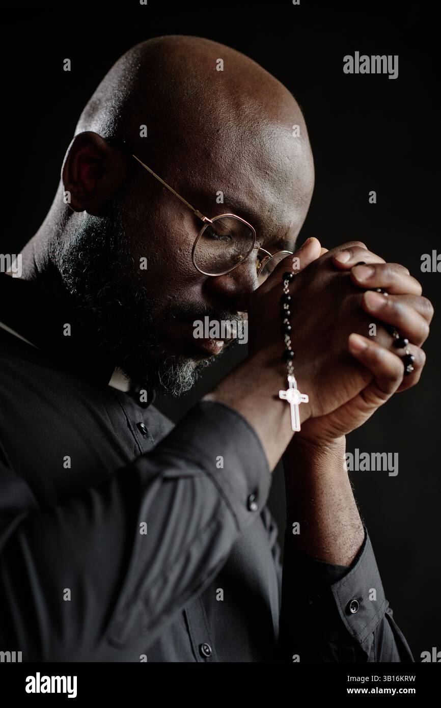 Low angle shot of standing still while praying silently alone in dark ...