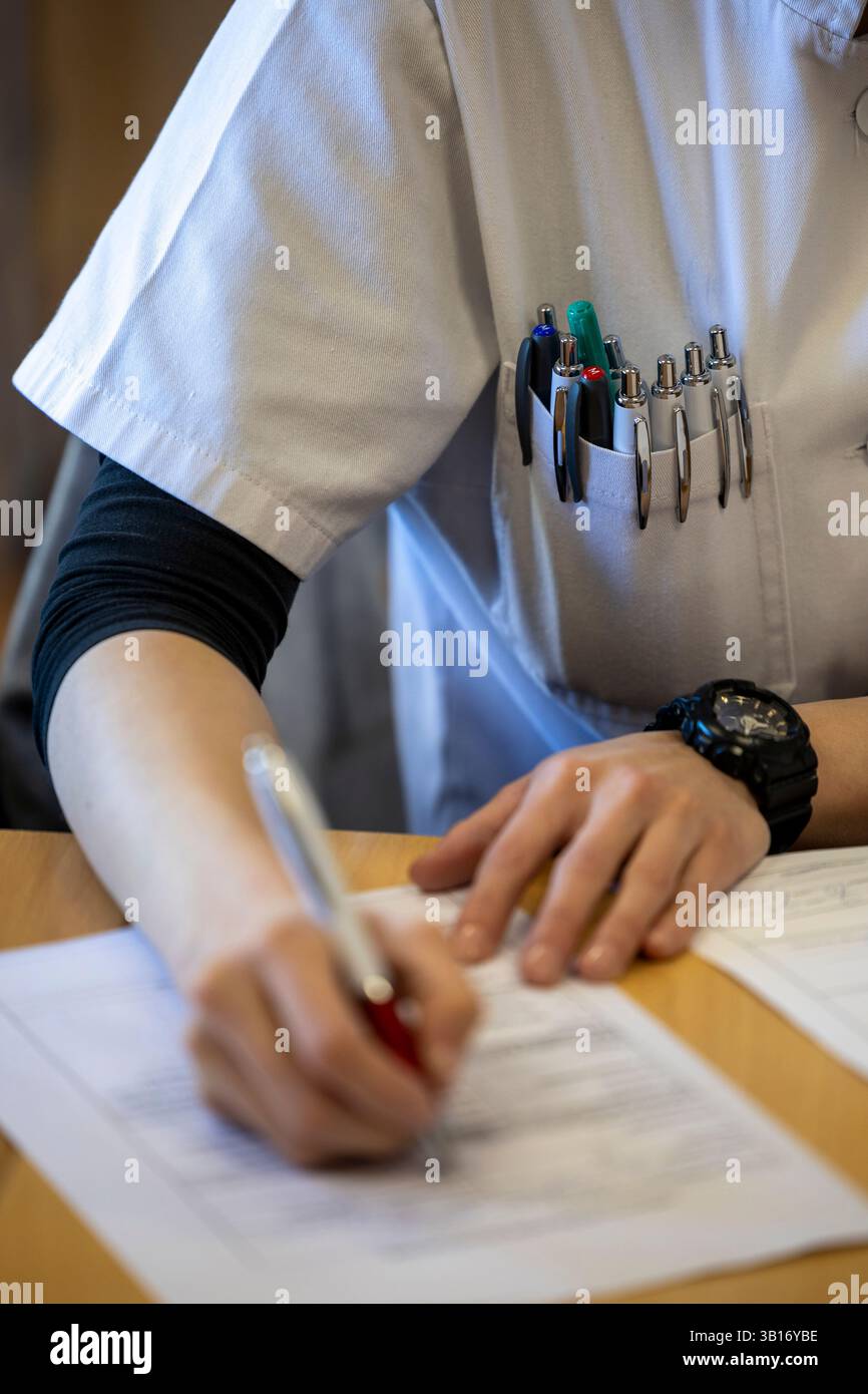 Female healthcare professional focuses on writing notes at desk ...