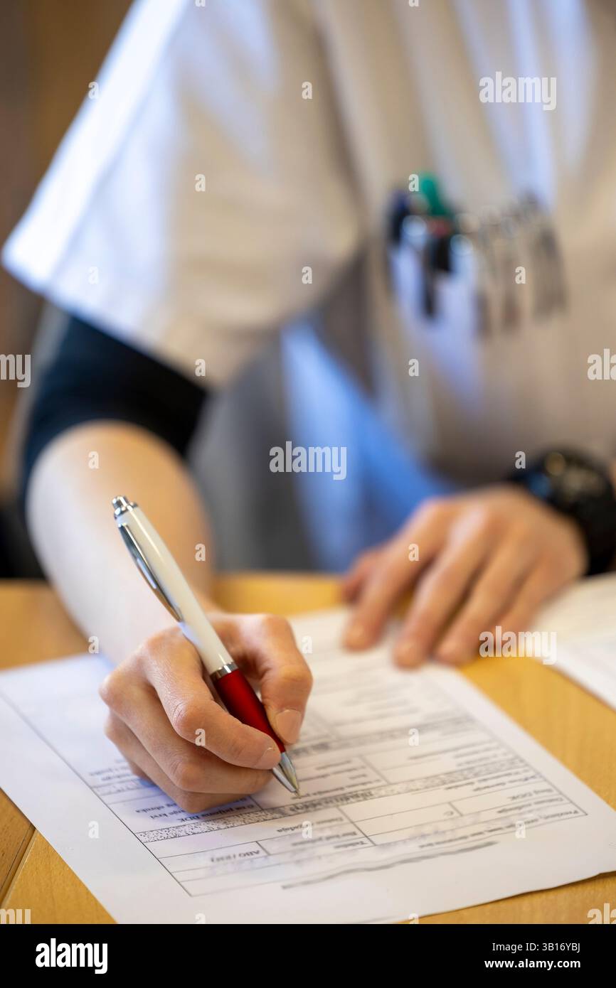 Female healthcare professional focuses on writing notes at desk ...