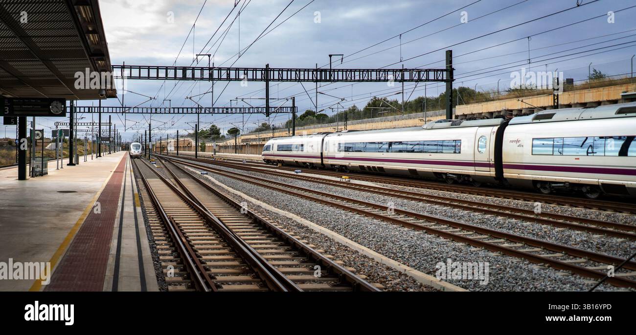 High-speed train passing through a modern railway station with multiple ...