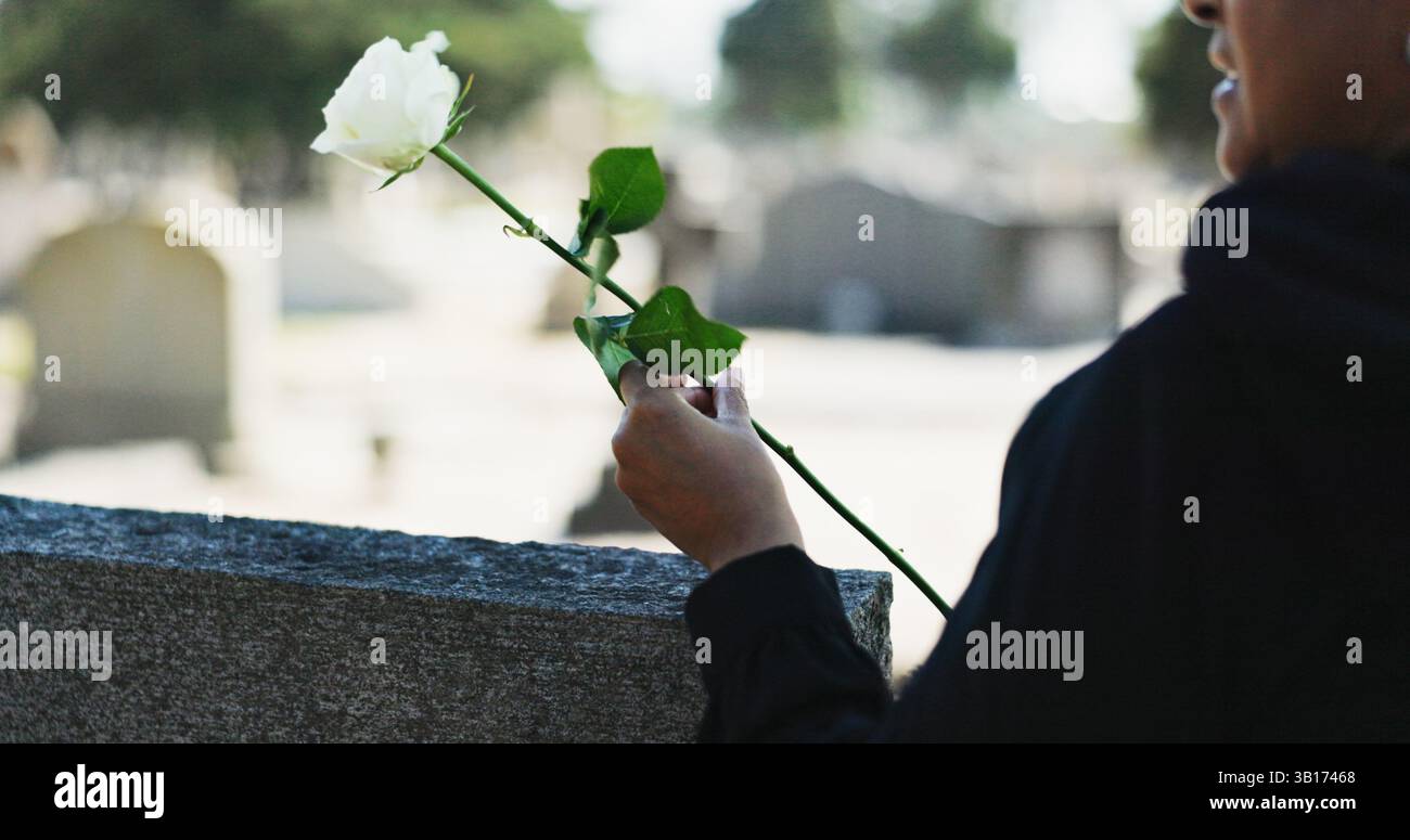 Hand, flower and person at gravestone for funeral, grief and memorial service outdoor at ...