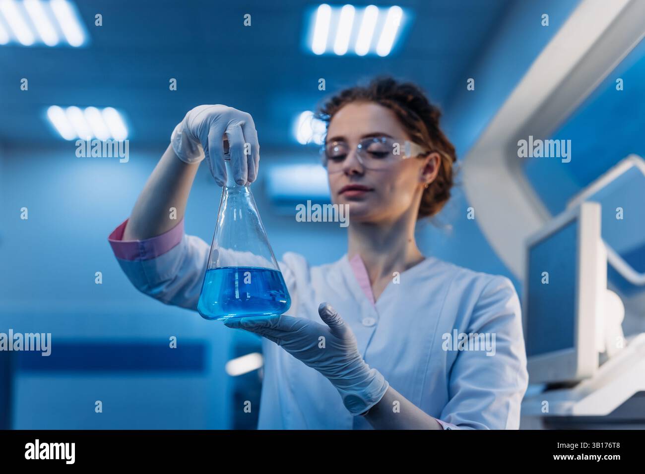 Female medical scientist in goggles holding chemical liquid into test ...