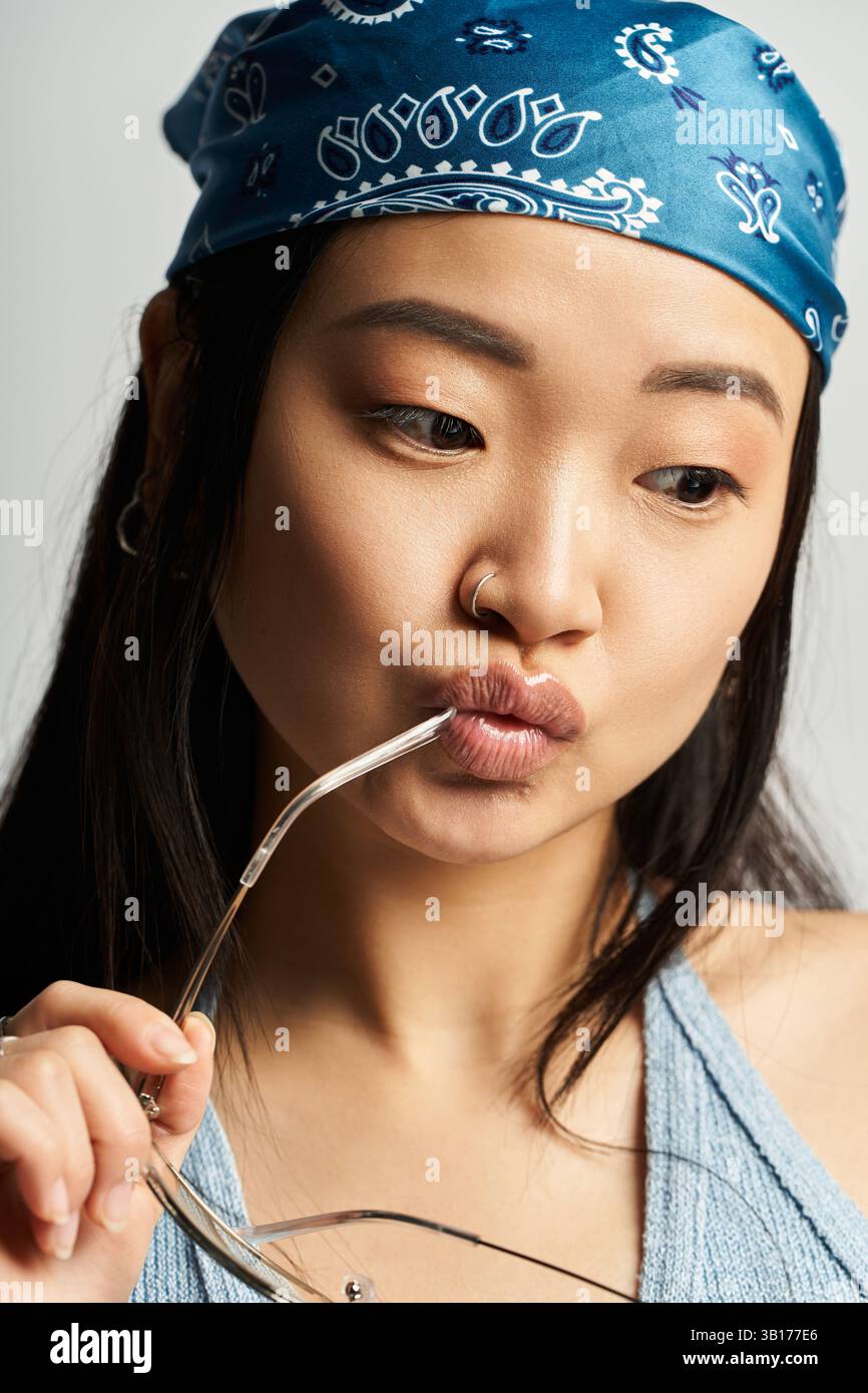 In a stylish setting, a beautiful young Asian woman playfully pouts and ...