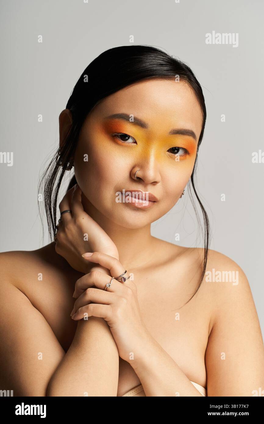 A young Asian woman poses gracefully with bold makeup and a serene ...