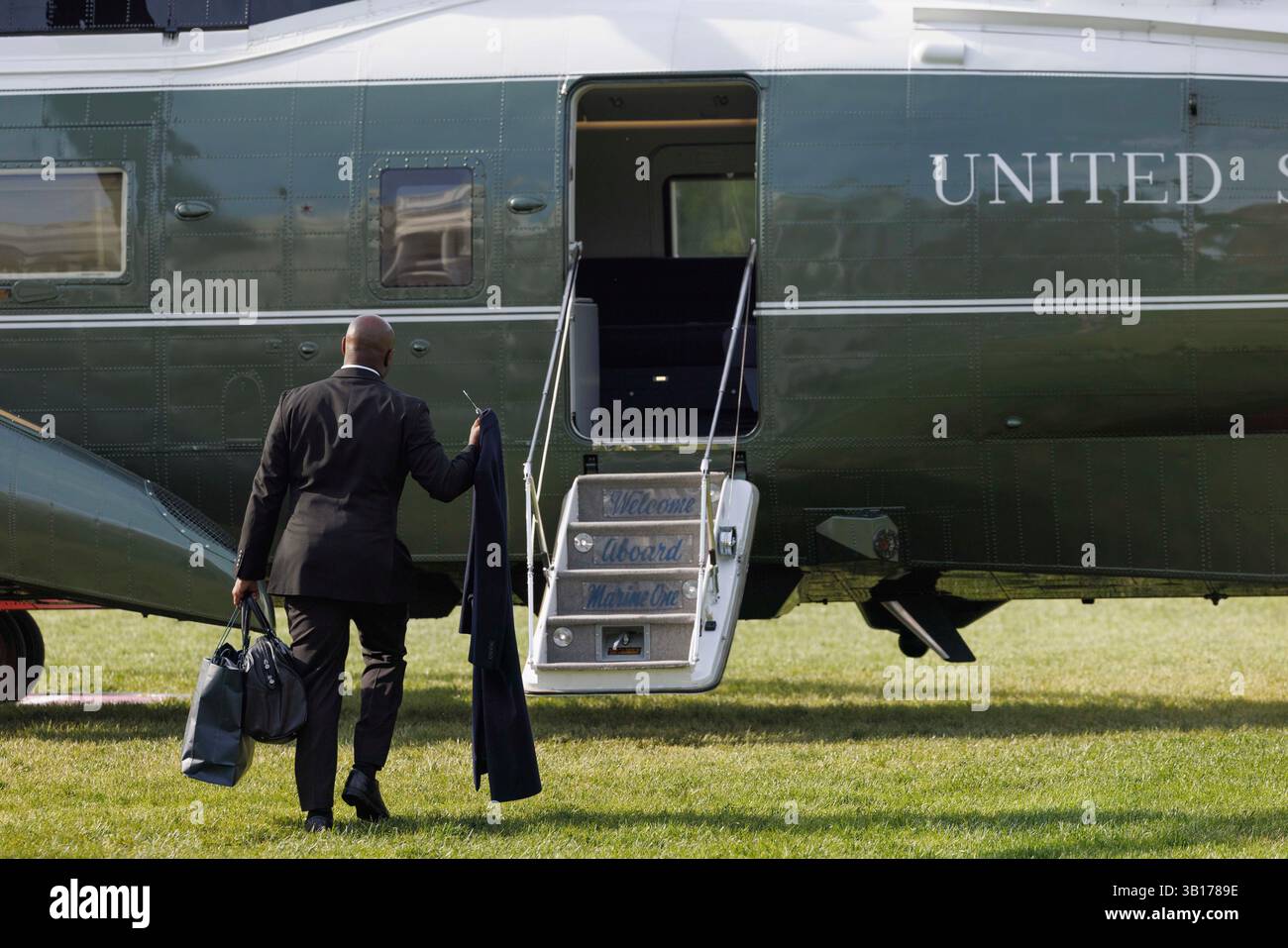A White House staffer carries clothes onto Marine One, as United States ...