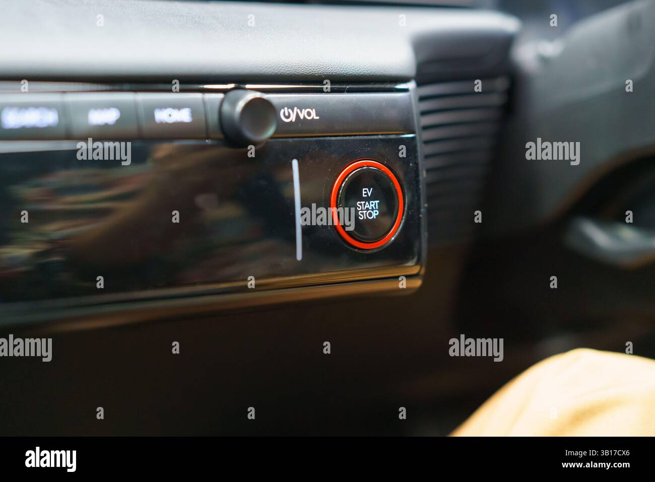 modern EV start-stop button beside a volume control knob on a sleek ...