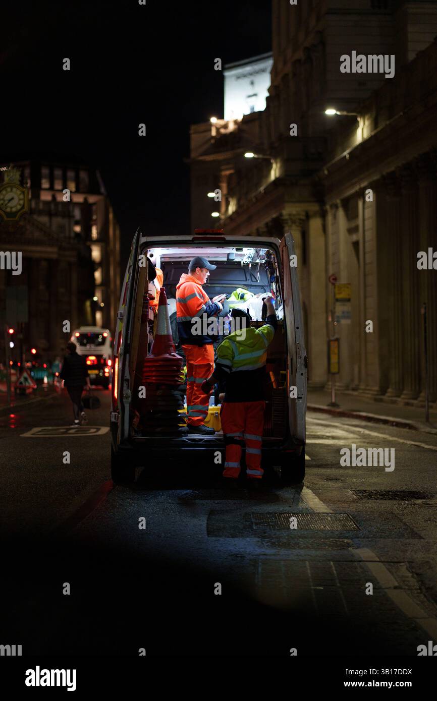 Workmen in high-visibility clothing prepare equipment from their van at ...