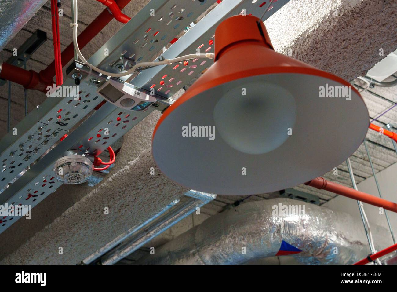 Low angle view of an orange industrial lamp, fire alarm, motion sensor ...