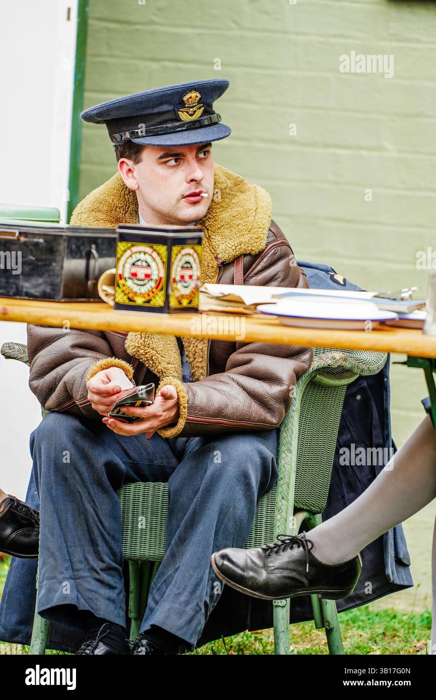 A man in a World War II RAF uniform smokes a cigarette while holding a ...