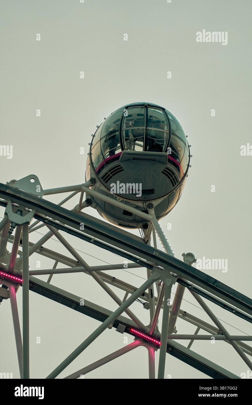 A glass pod of the London Eye Ferris wheel against a pale sky, offering ...