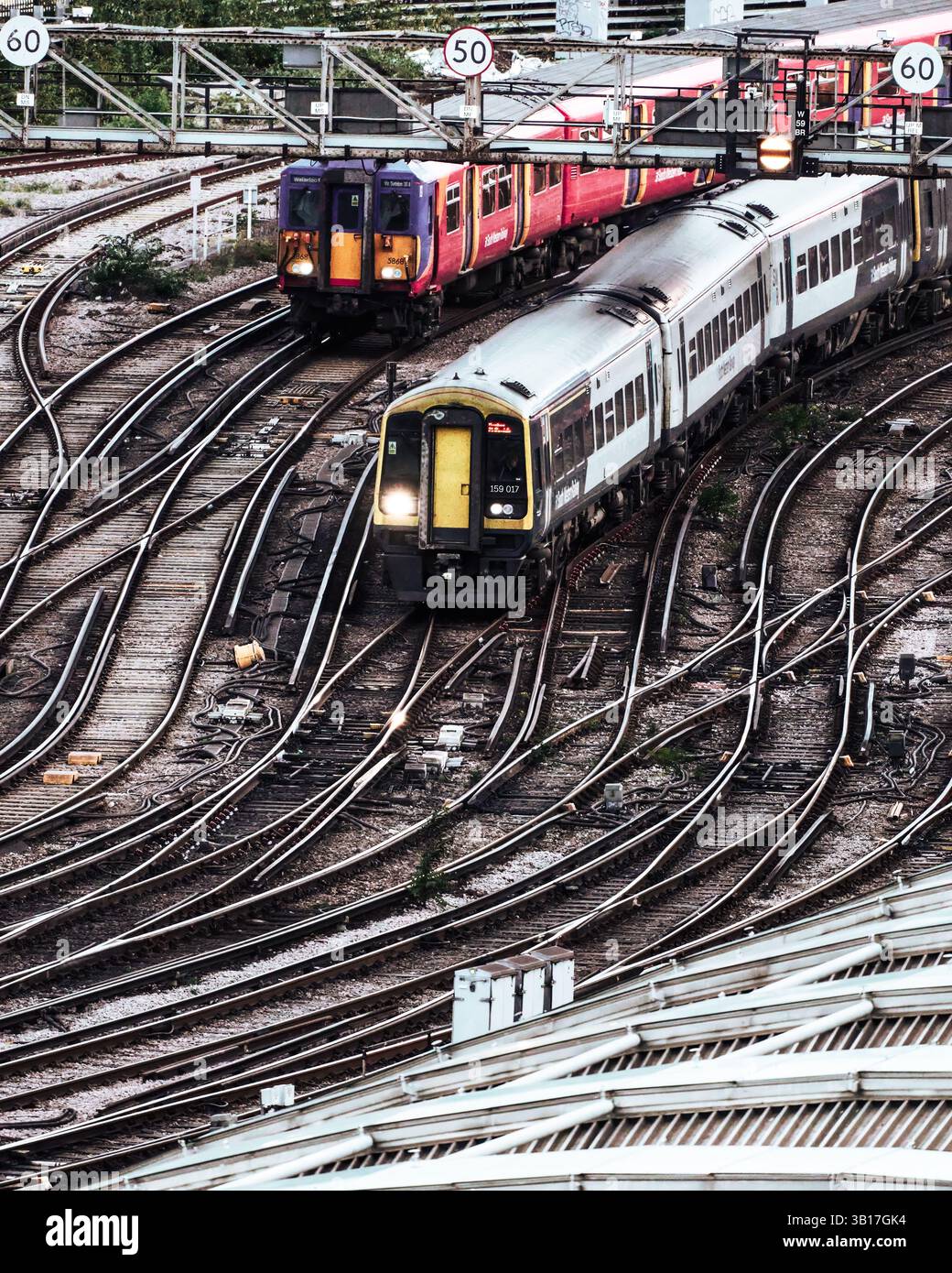 Commuter trains navigate a complex network of railway tracks at a busy ...