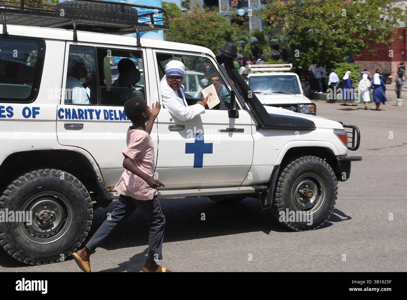 A boy runs behind a car carrying nuns to ask them for money after the ...