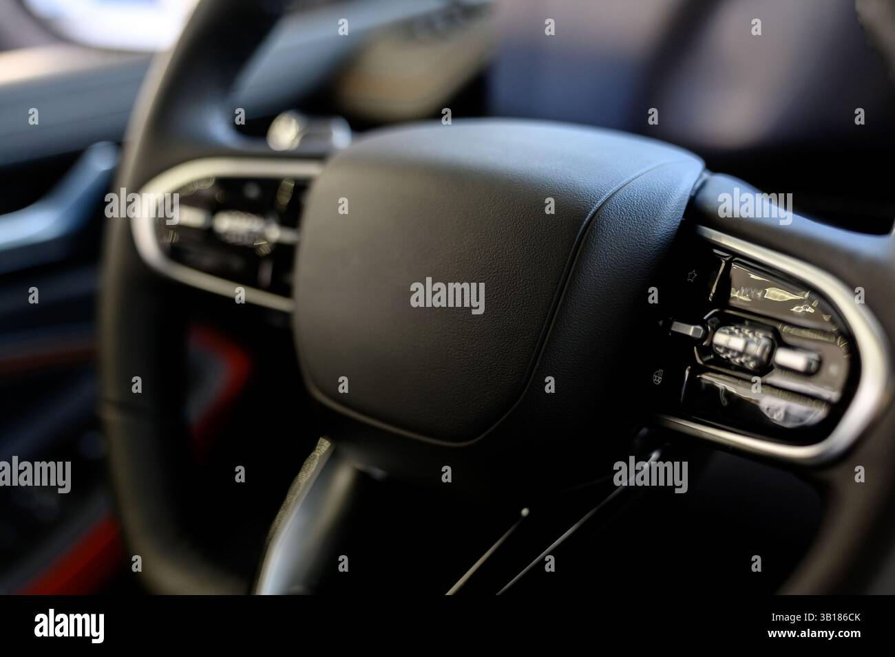 A close-up of a modern car's steering wheel, made of smooth black ...
