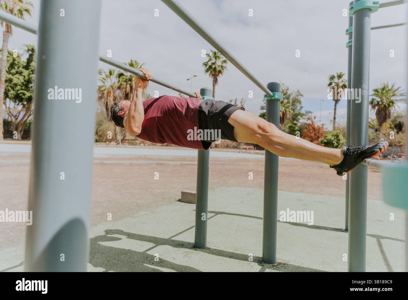 A strong man is doing Australian pull ups at a calisthenics outdoor gym ...