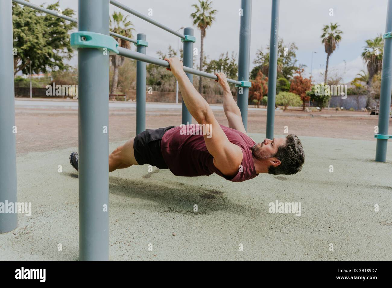 A man is doing Australian pull ups doing his workout outside ...