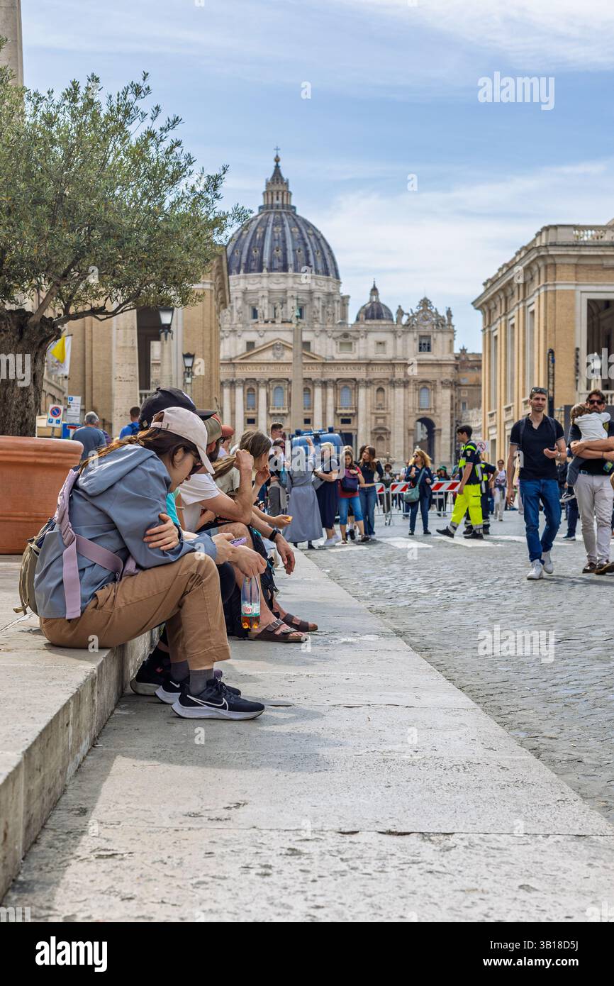 Vatican - April, 23, 2025: People sitting along the street to basilica ...