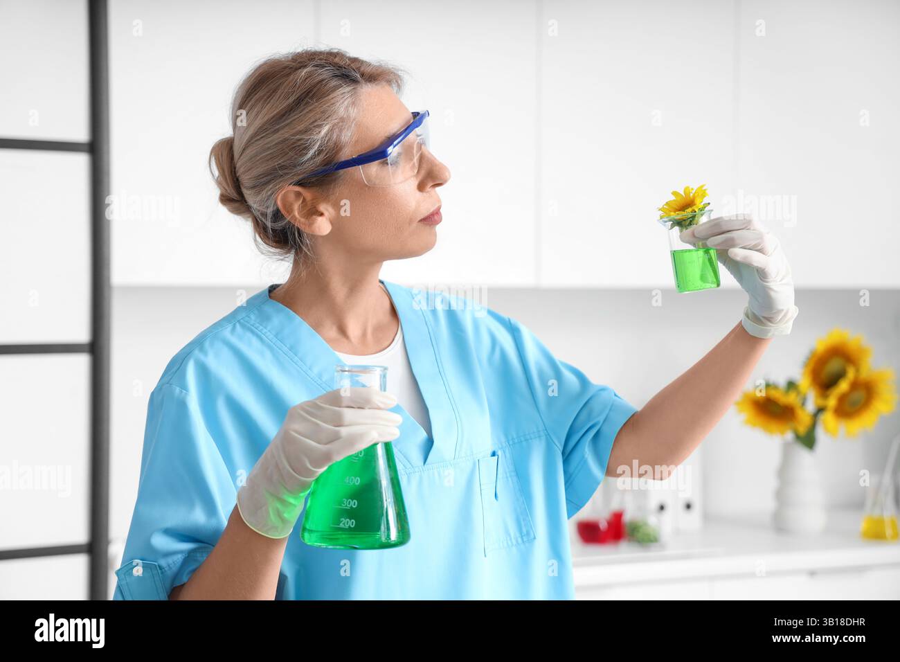 Female scientist with flasks of samples and sunflowers working in ...