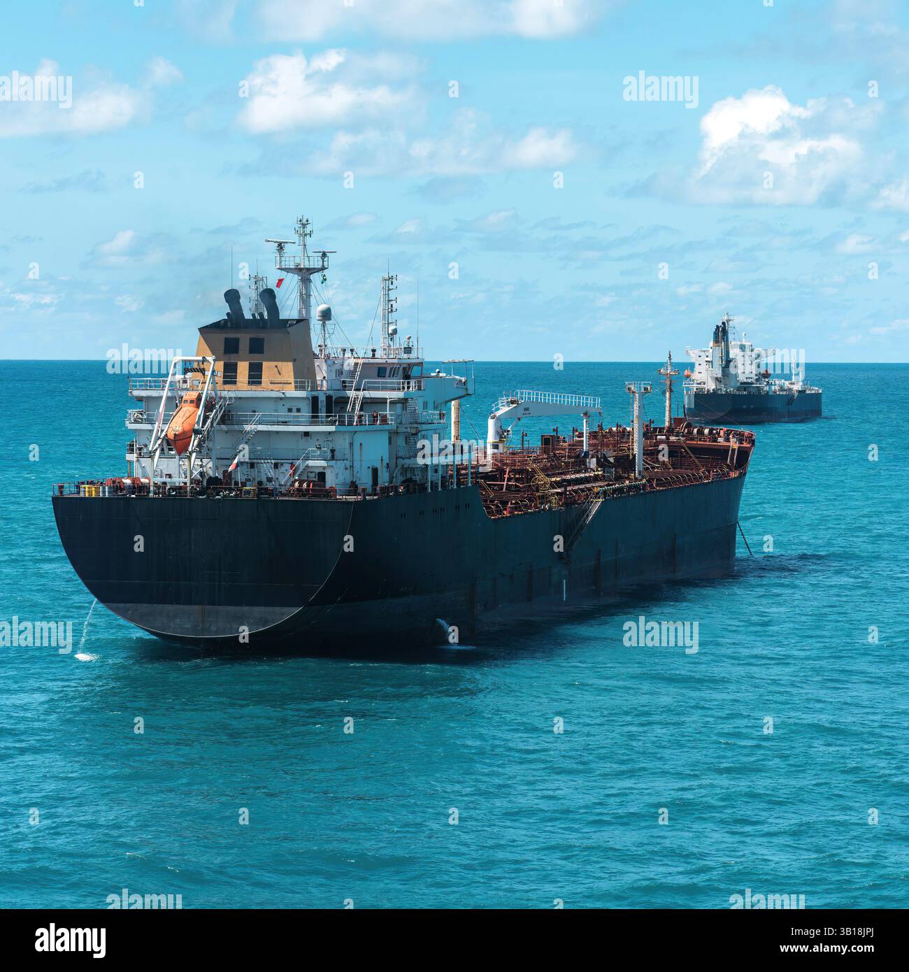 Two large cargo ships sail through calm ocean waters, showcasing their impressive size and ...