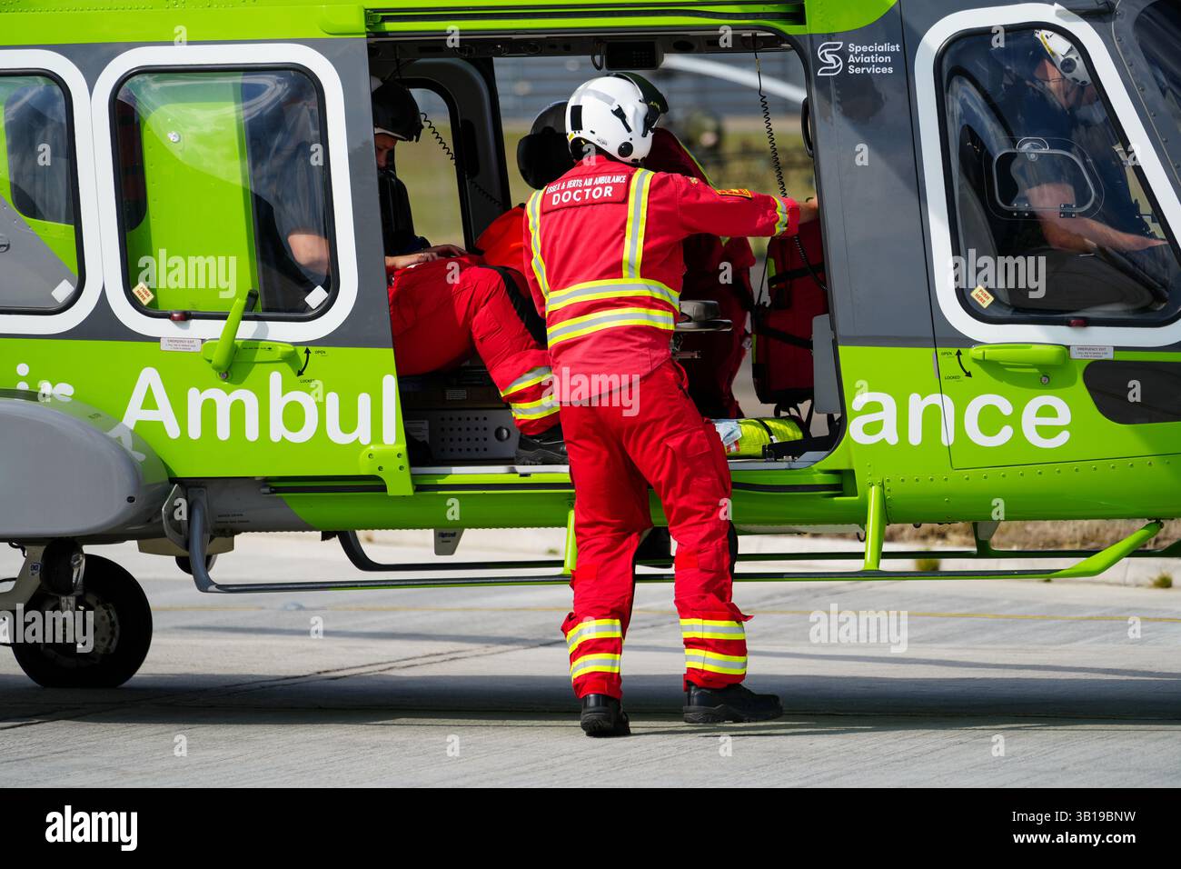 An air ambulance doctor exits a green helicopter, preparing for an ...