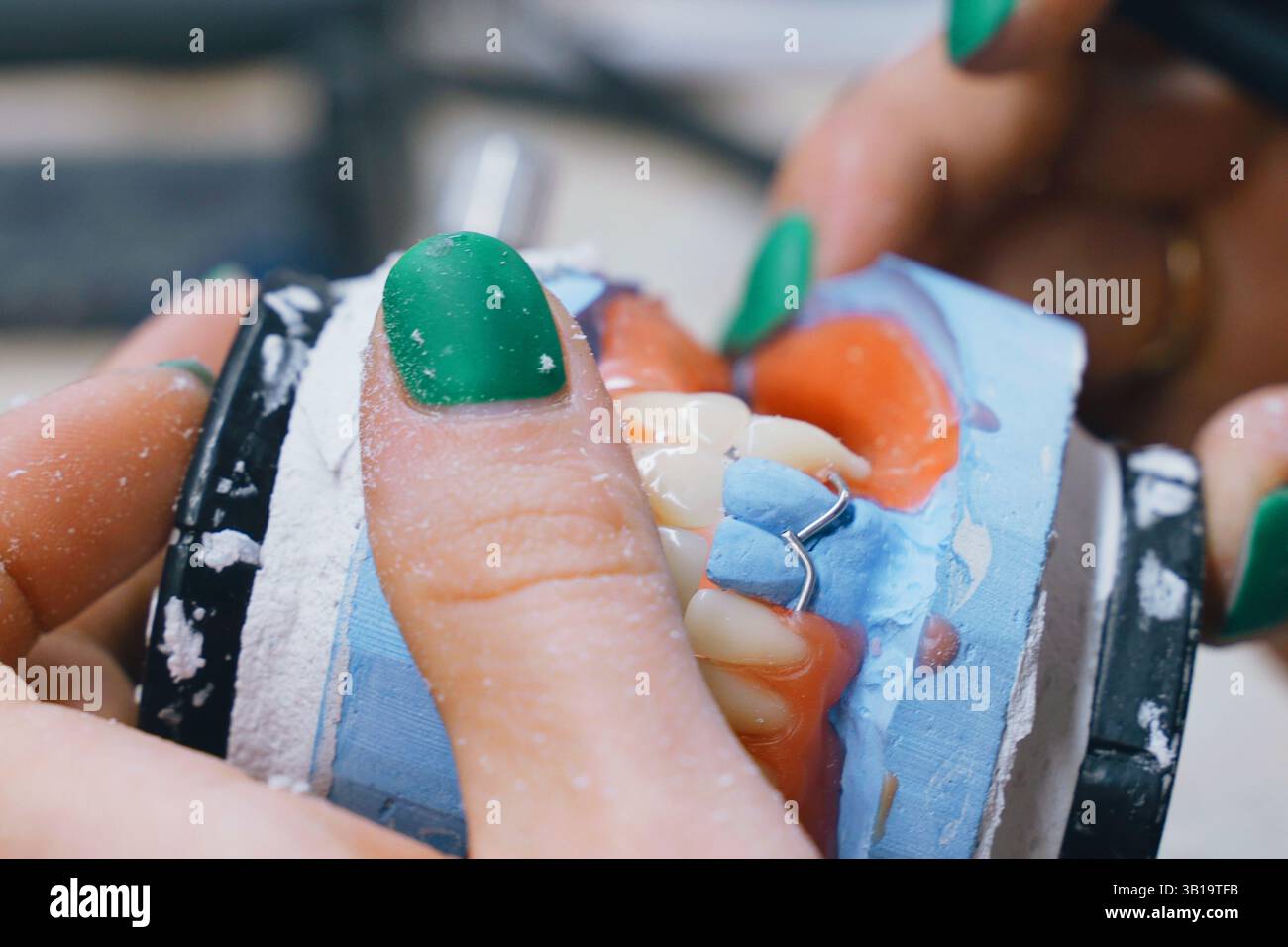 A dental technician, focused and detail-oriented, checks the bite fit ...
