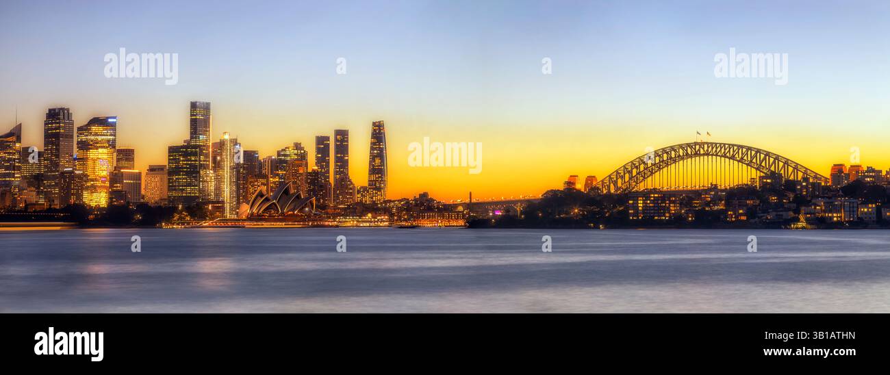 Bright sunset colours in the sky over City of Sydney harbour shore ...