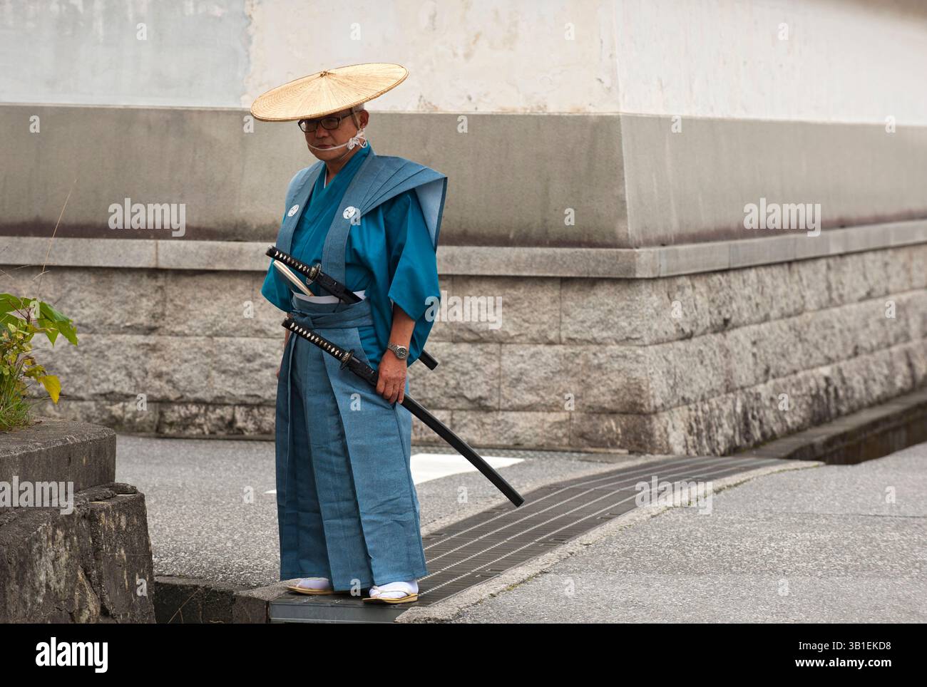 Man dressed in formal samurai attire holding a katana sword stands ...