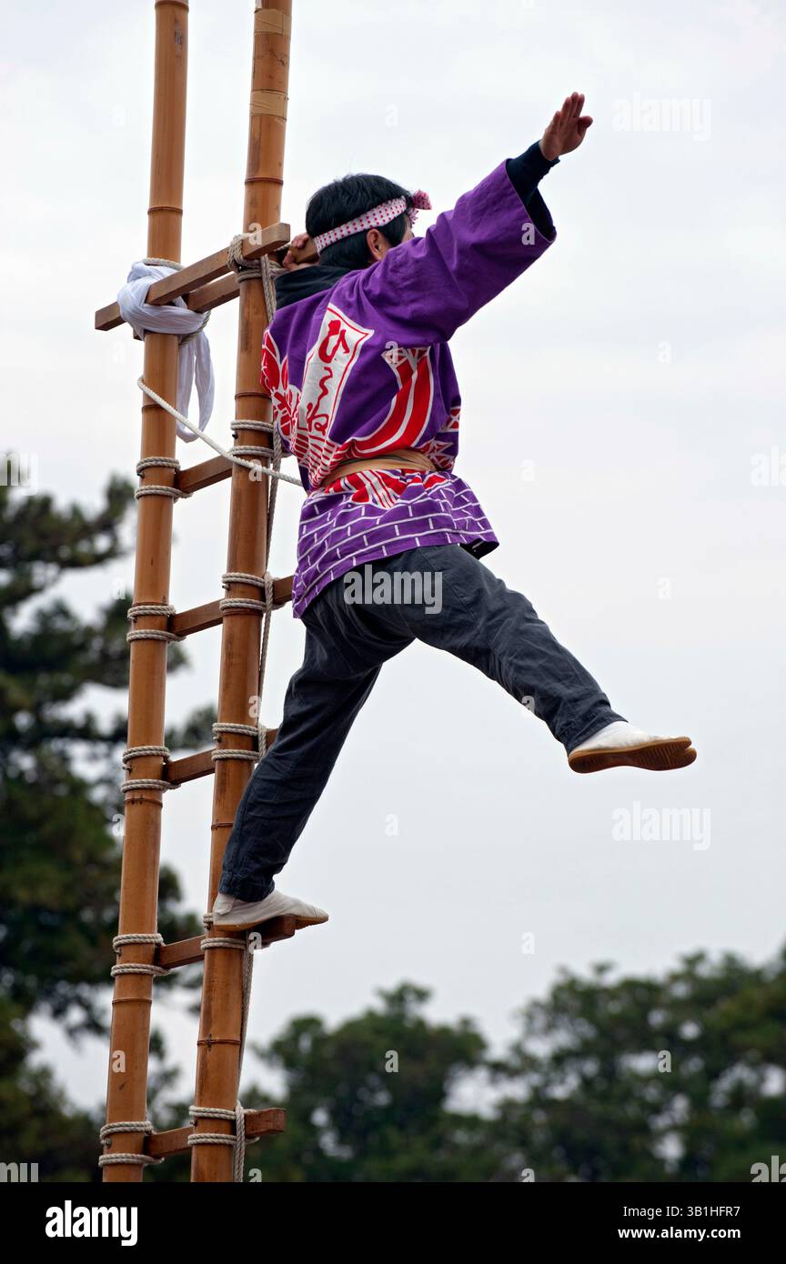 Traditional Japanese fireman performing stunts atop a bamboo ladder ...