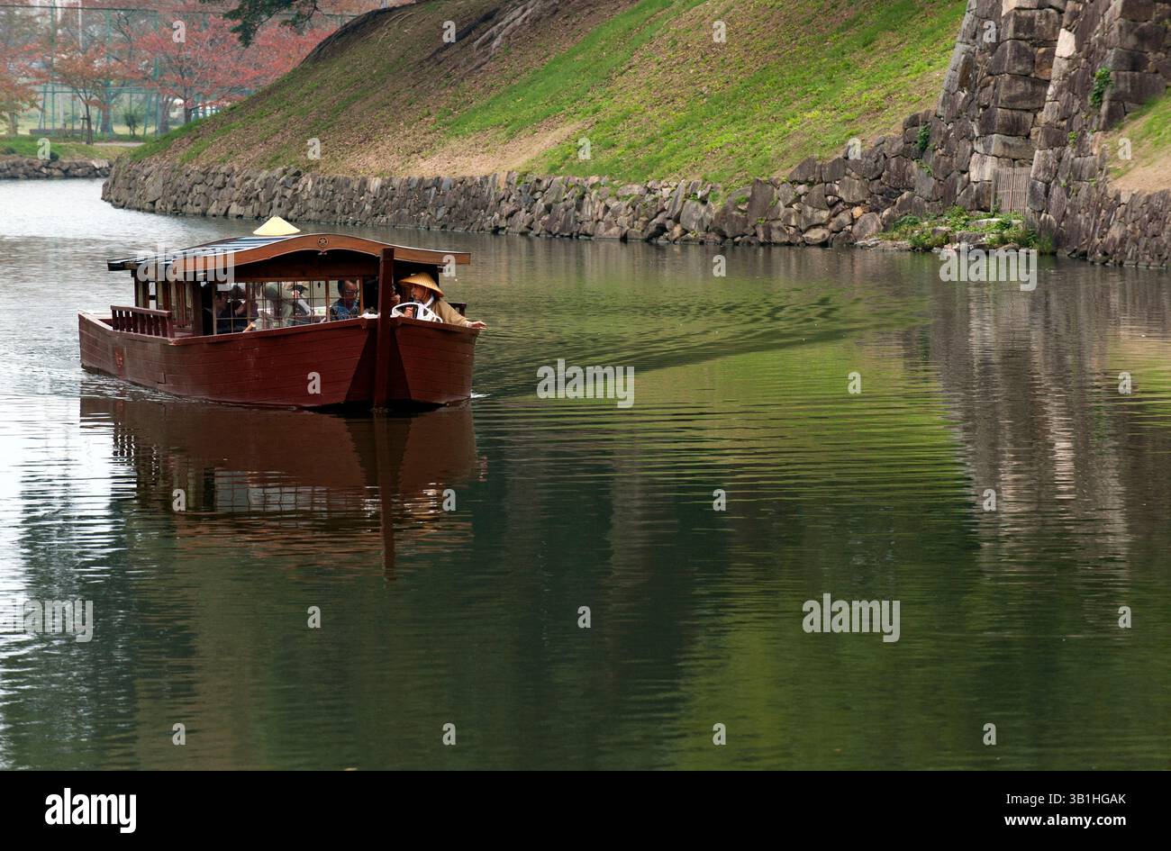 A sightseeing canal boat makes is way around the Hikone Castle moat in ...