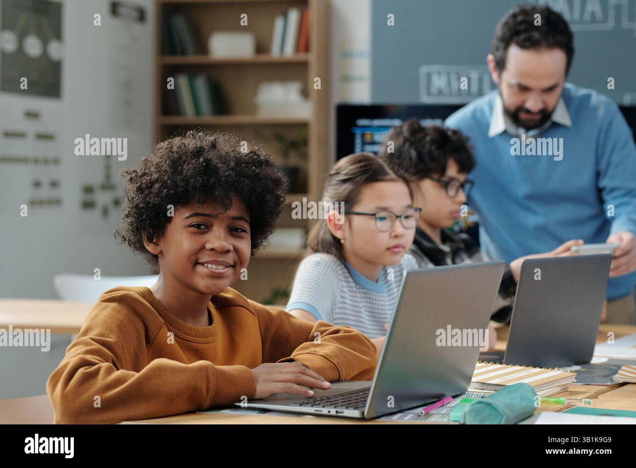 Children Studying Using Laptops With Teacher Assisting Stock Photo - Alamy