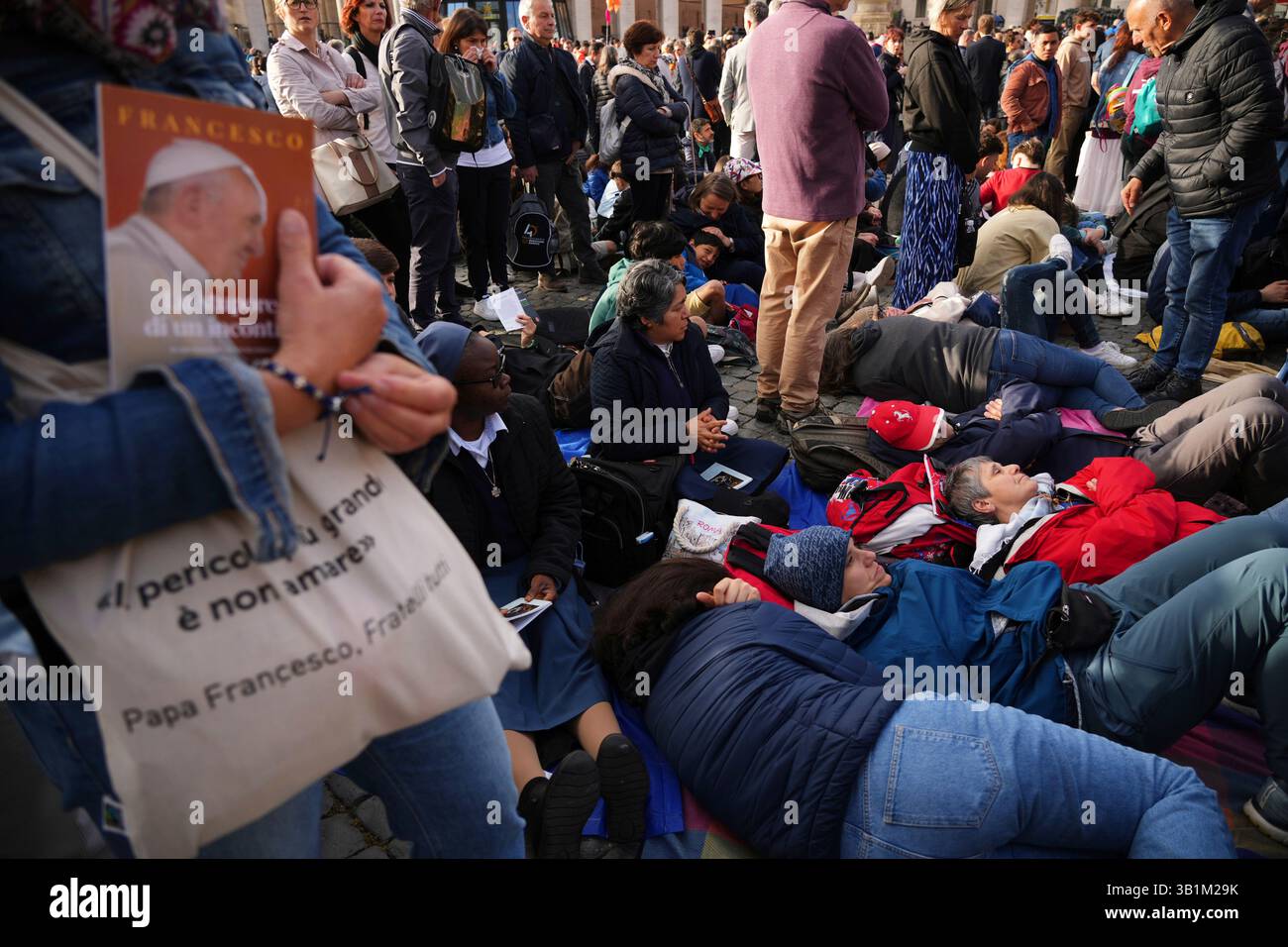 Faithful rest on the ground outside St Peter's Basilica waiting for the ...