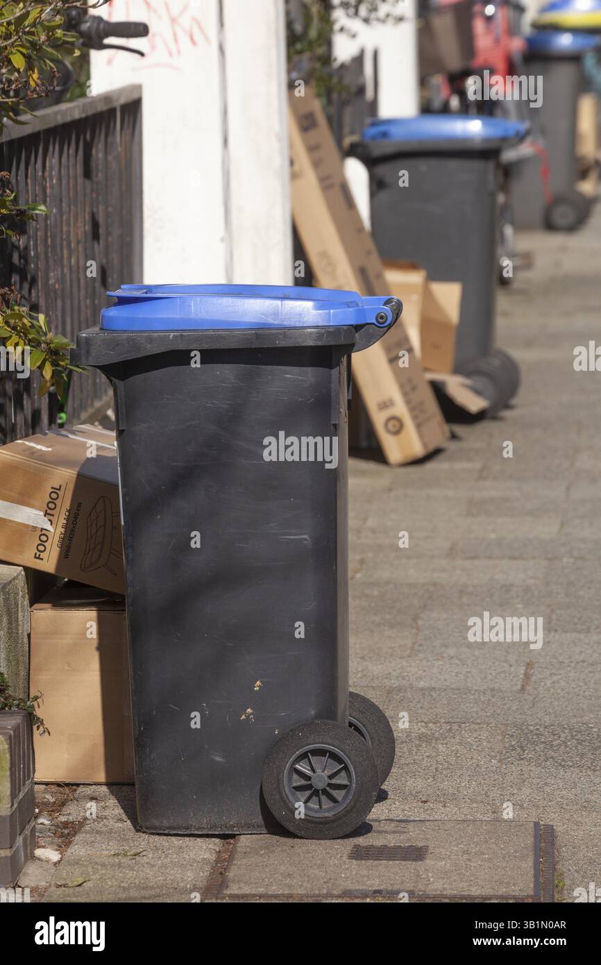 Blue bins for plastic waste and old cardboard standing on the pavement ...