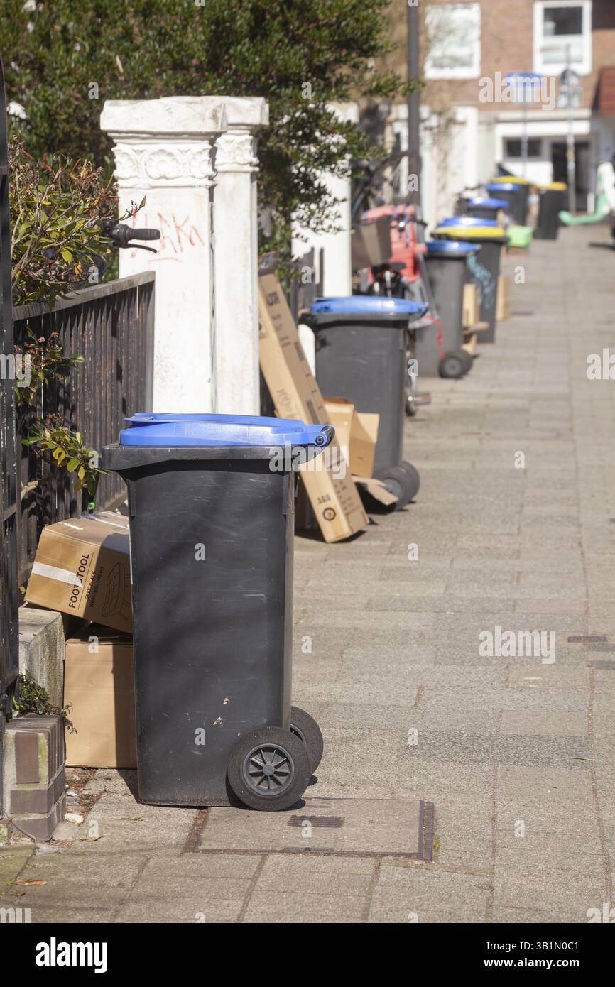 Blue bins for plastic waste and old cardboard standing on the pavement ...