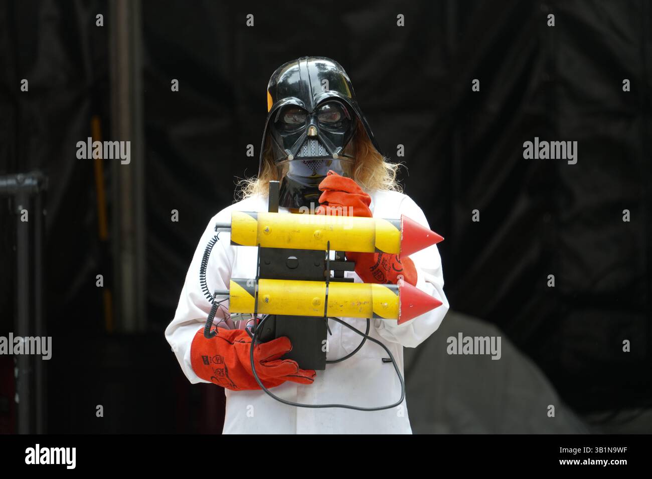 A person wearing a Darth Vader mask and lab coat holds a twin-rocket ...