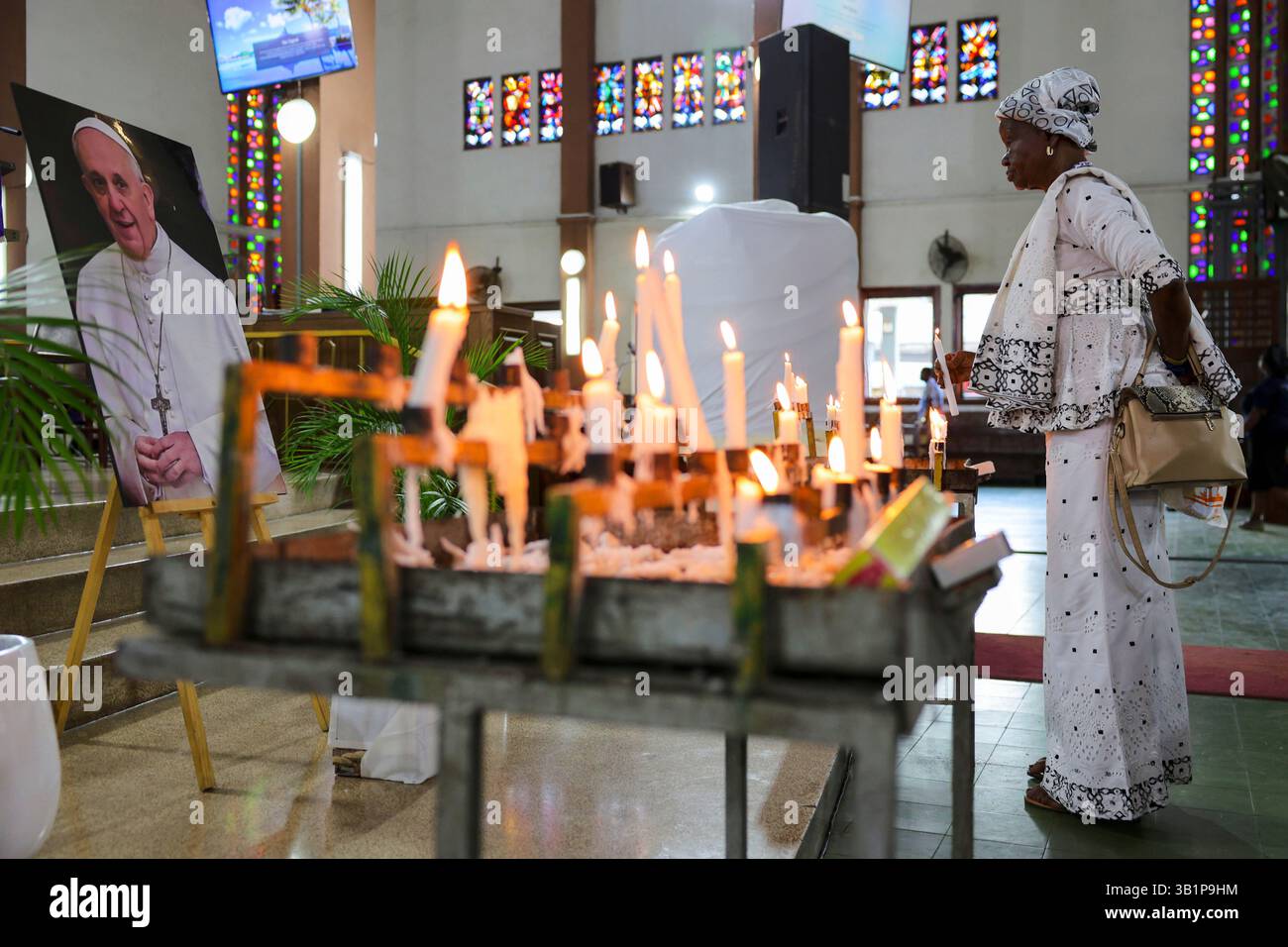 A parishioner lights a candle in front of the late Pope Francis ...