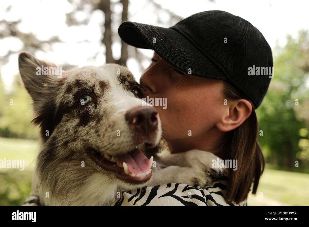 Close-up of a young woman in a black cap lovingly kissing her happy ...